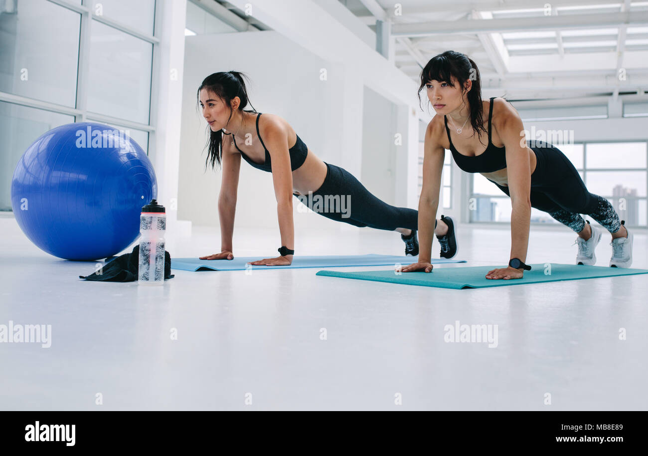 Two women doing push ups together in gym. Tough females working out in ...