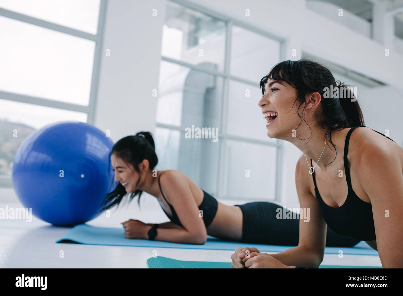 Fit girls smiling while exercising together in gym. Healthy young women ...