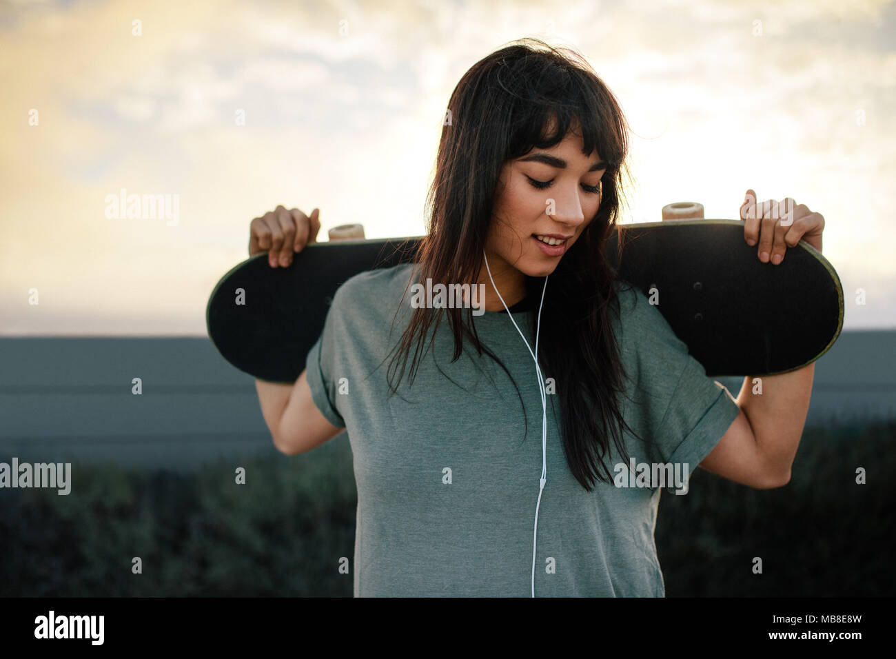 Female skateboarder standing outdoors holding her skateboard. Beautiful ...