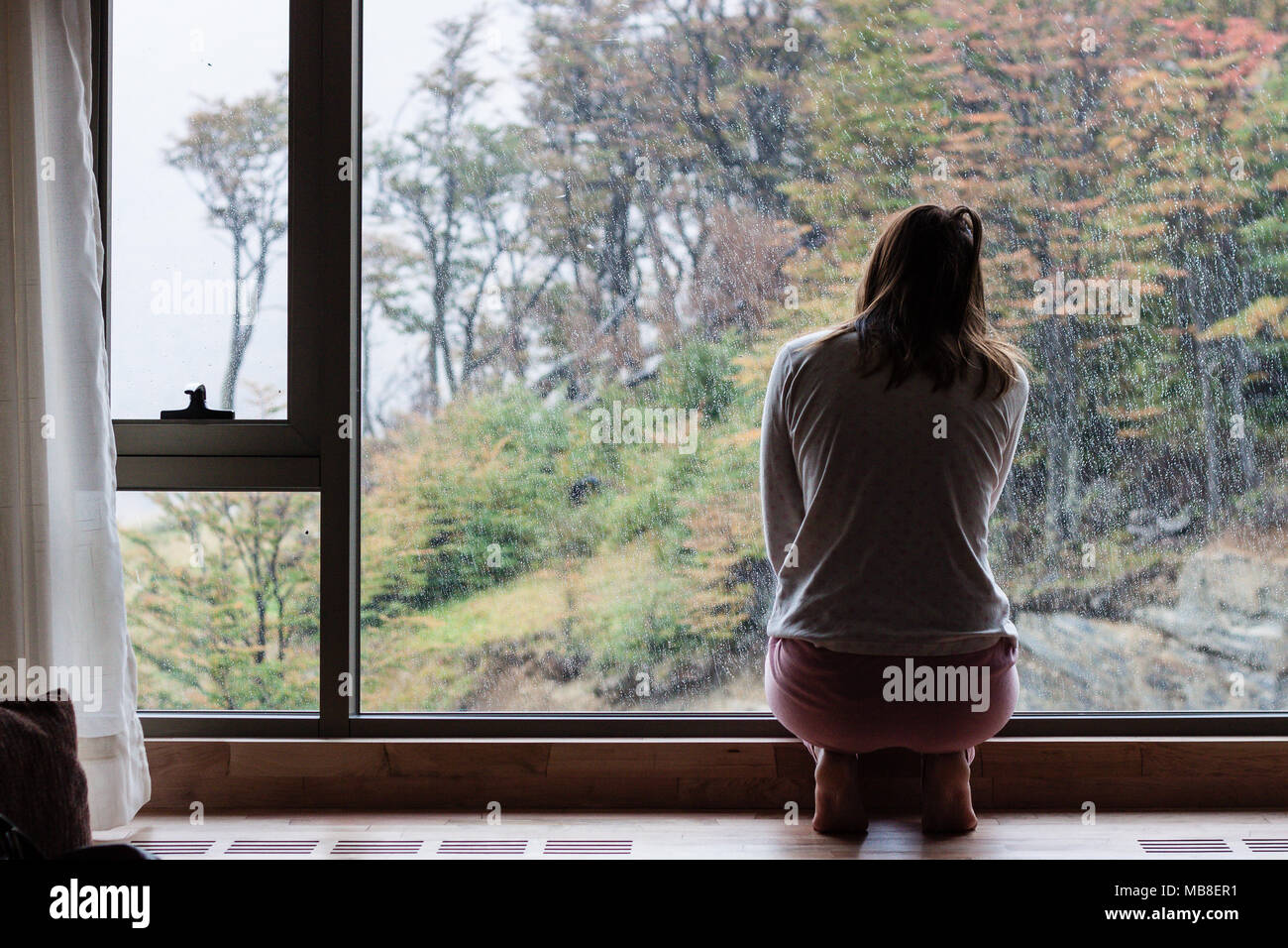 Young woman looking out the window at the rain Stock Photo - Alamy