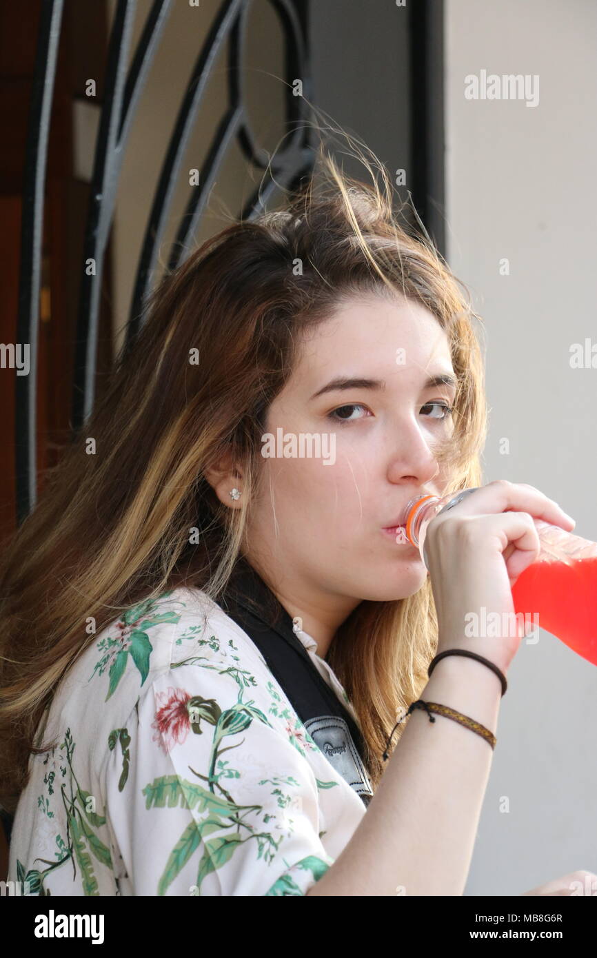 Blonde angry girl drinking bottle of red liquid Stock Photo - Alamy