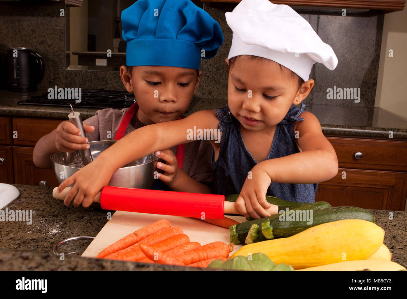 Siblings eating and cooking in the kitchen Stock Photo - Alamy