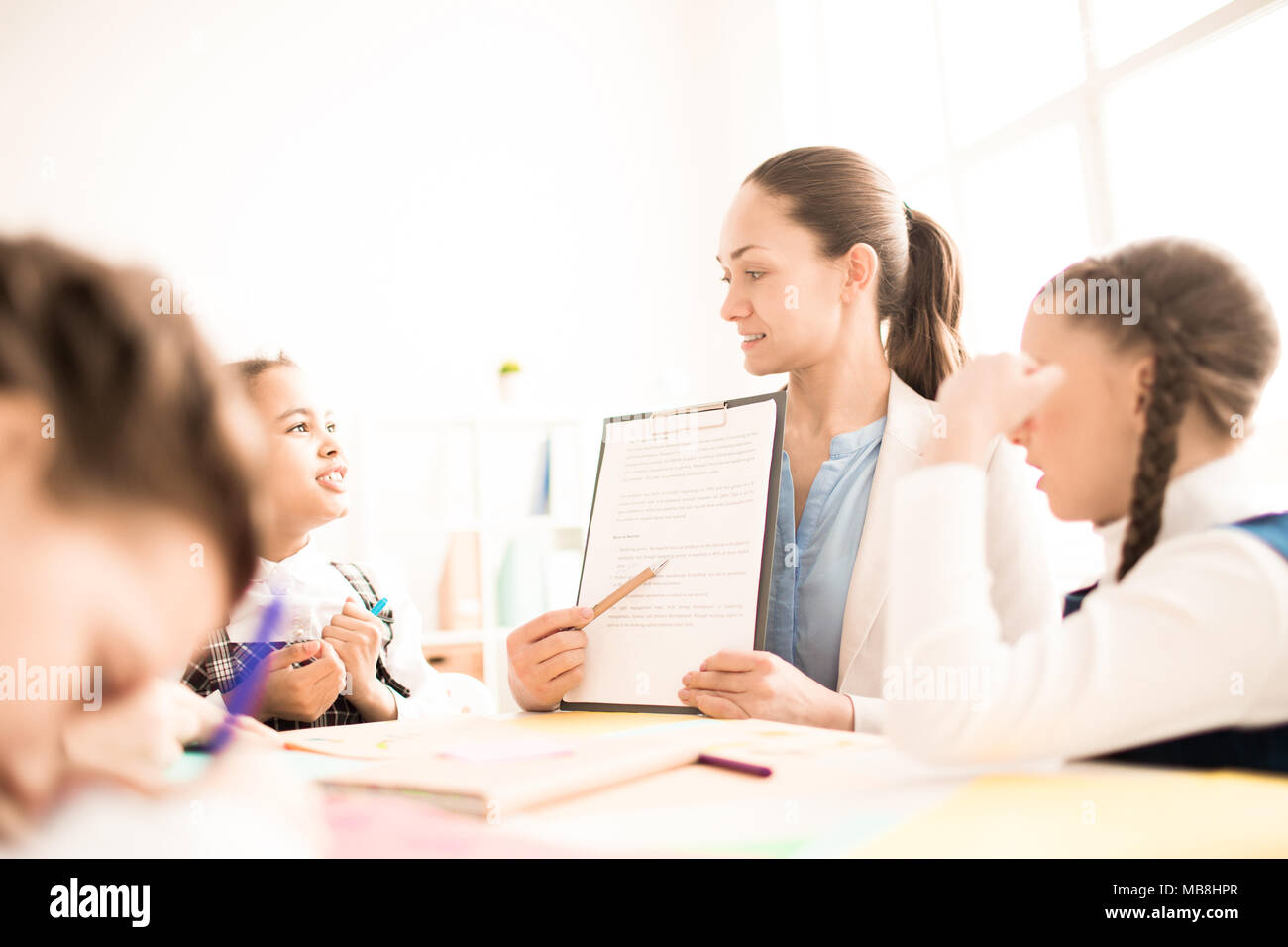 Diligent schoolkids and their teacher talknig at lesson Stock Photo - Alamy