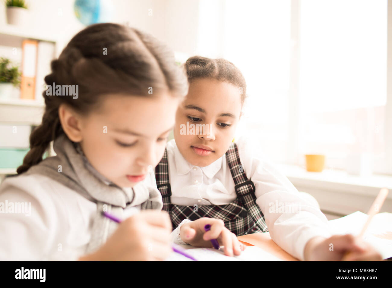 Little girls studying at the table together during a lesson Stock Photo ...