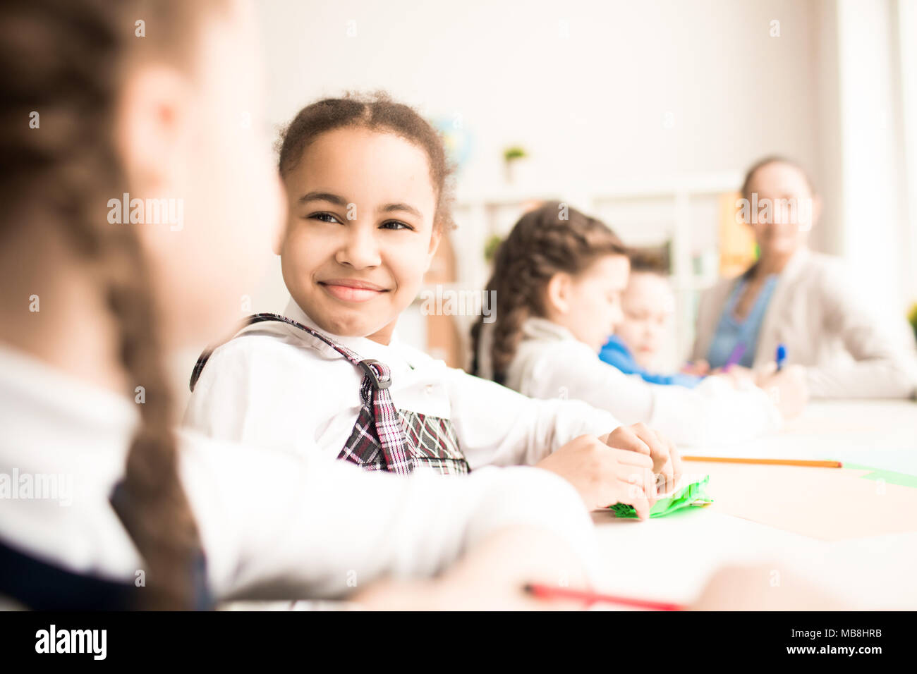 Schoolgirl communicating with her classmate during a lesson Stock Photo ...