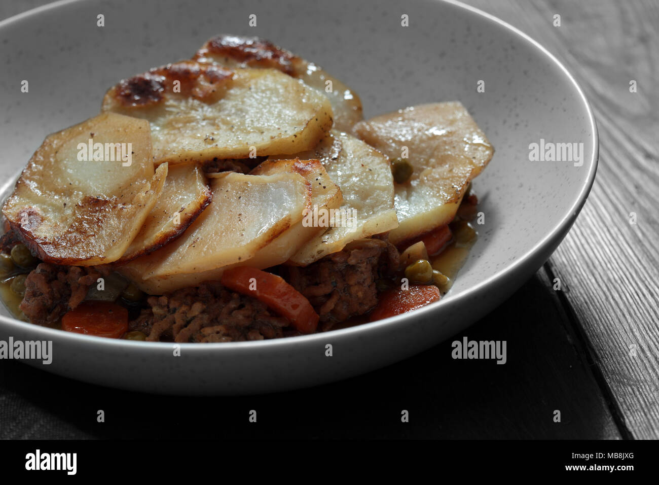 Potato hot pot on a wooden background with minced beef and vegetables ...