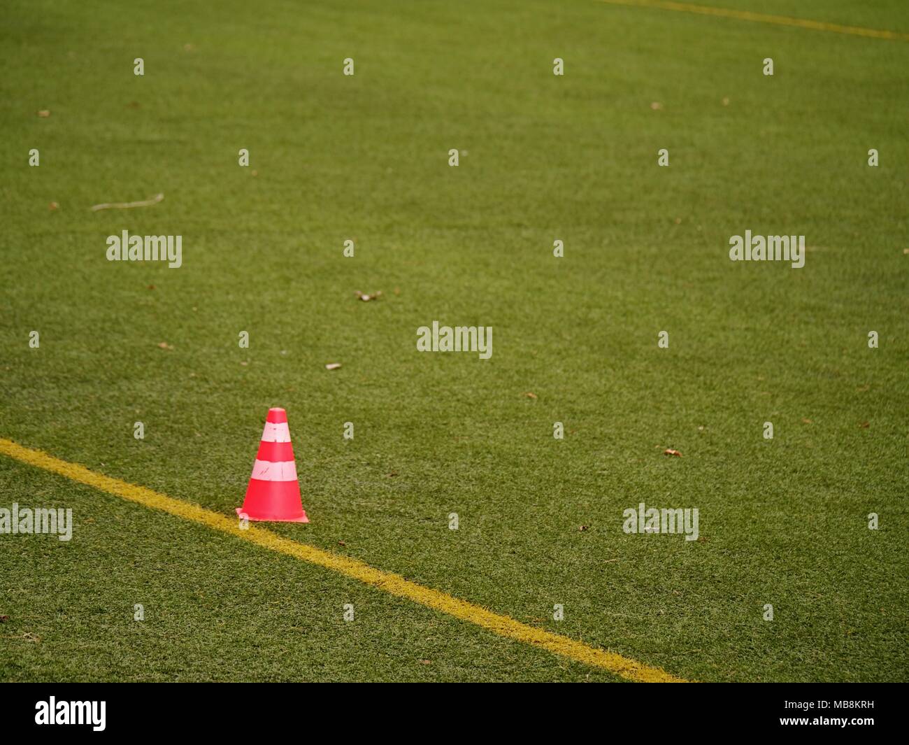 Bright red plastic cone on painted white line of soccer field. Football ...