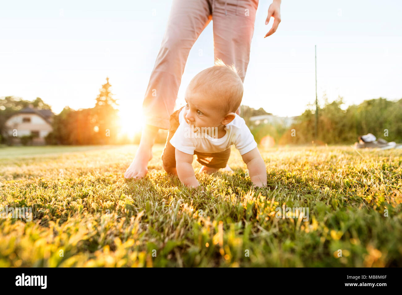 Baby boy with unrecognizable mother crawling outside Stock Photo - Alamy