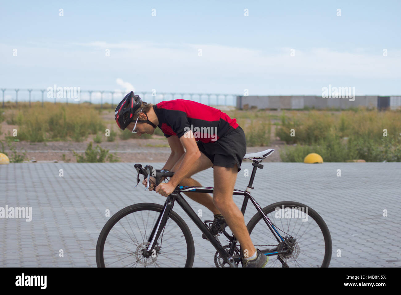 Professional bicycle rider in helmet and sportswear training on empty ...