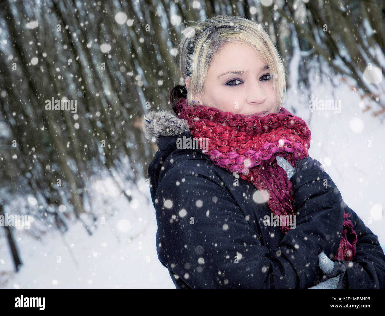 Pretty Woman wrapped up in Winter with snow falling Stock Photo - Alamy
