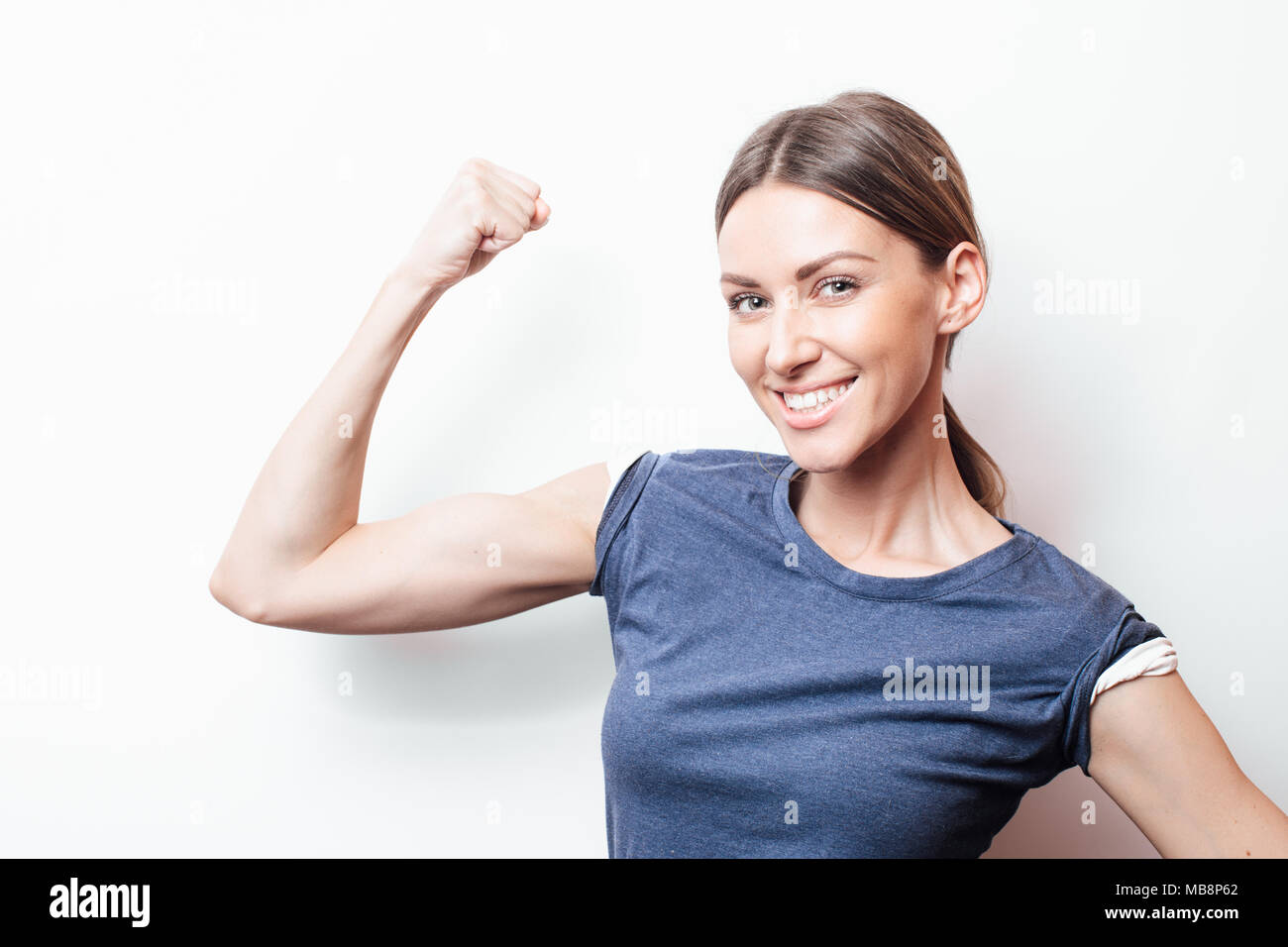 Beautiful young woman in blue shirt posing with arms raised. Portrait ...