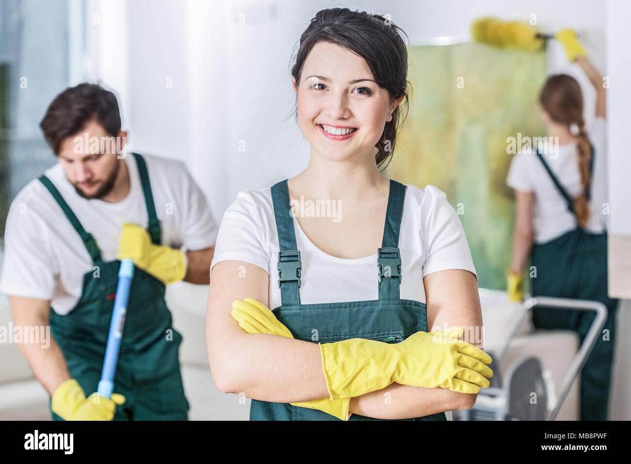 Smiling cleaning lady in a green uniform and yellow rubber gloves at ...