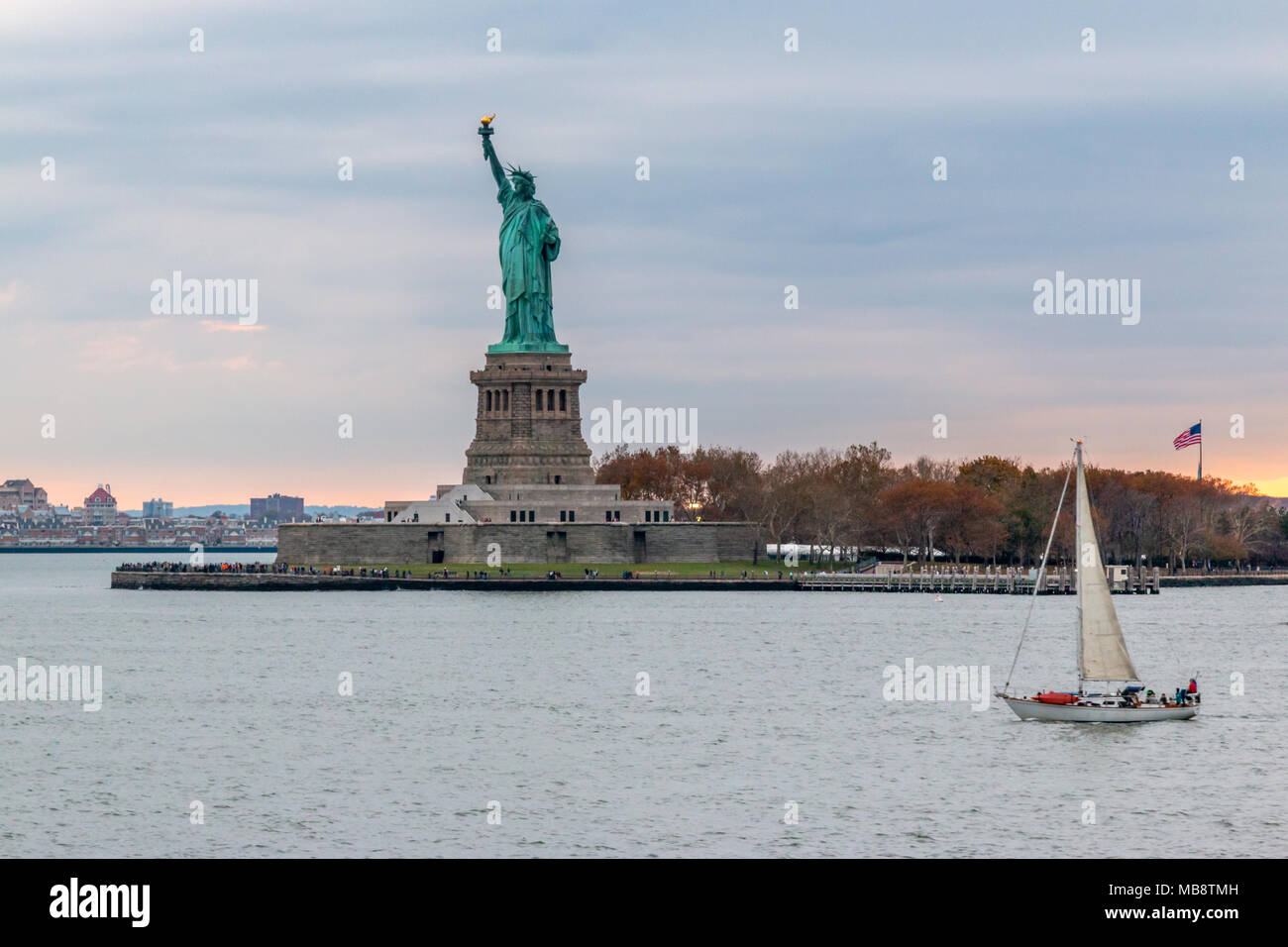 Sunset view of Statue of liberty with sail boat and american flag Stock ...