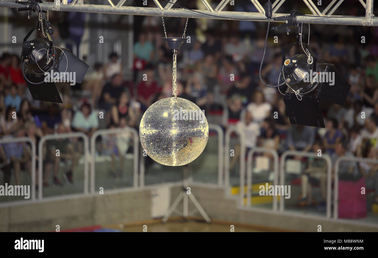 Big disco ball at the concert that reflects light directed at it in ...