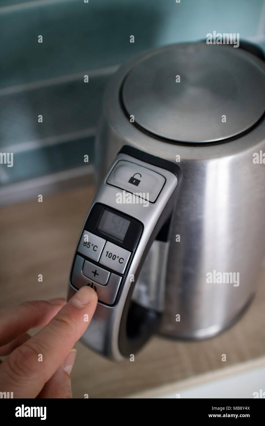 man hand click on the button iron electric kettle on the background of ...