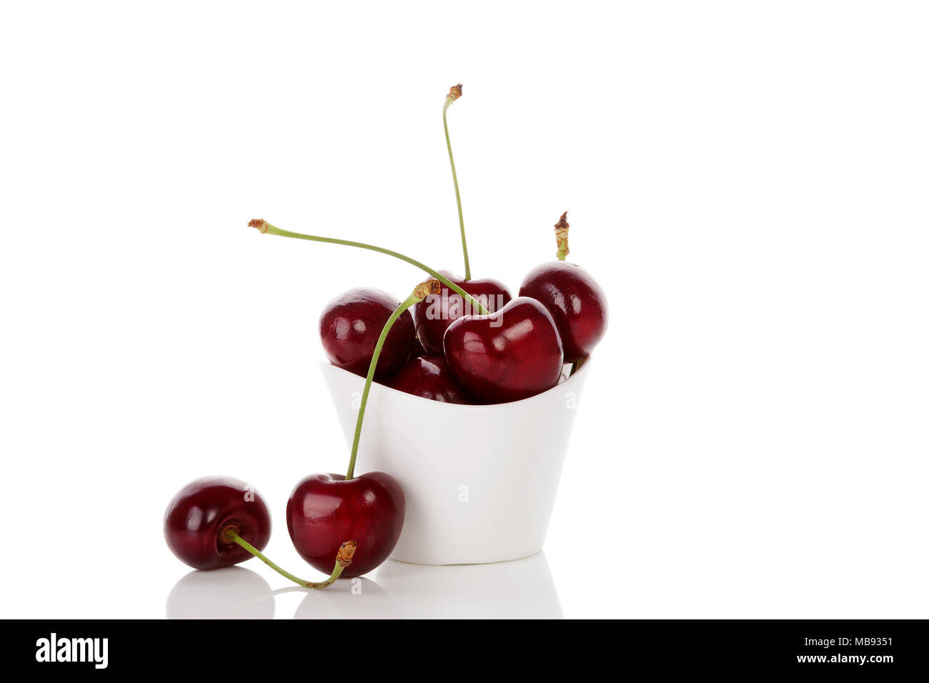 Delicious red cherries in white cup with reflection isolated on white ...