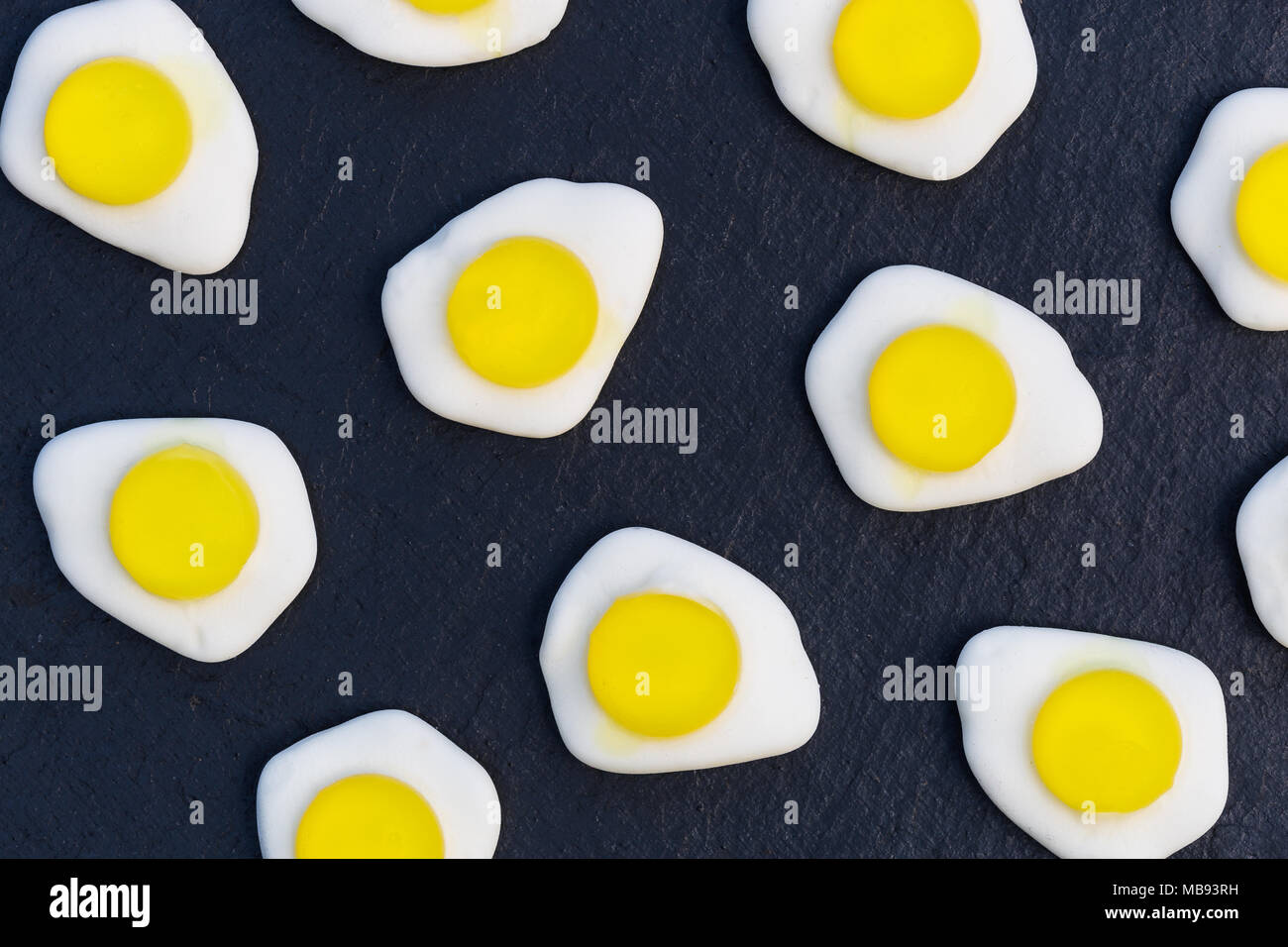 Fried eggs candy sweets overhead on dark background Stock Photo - Alamy