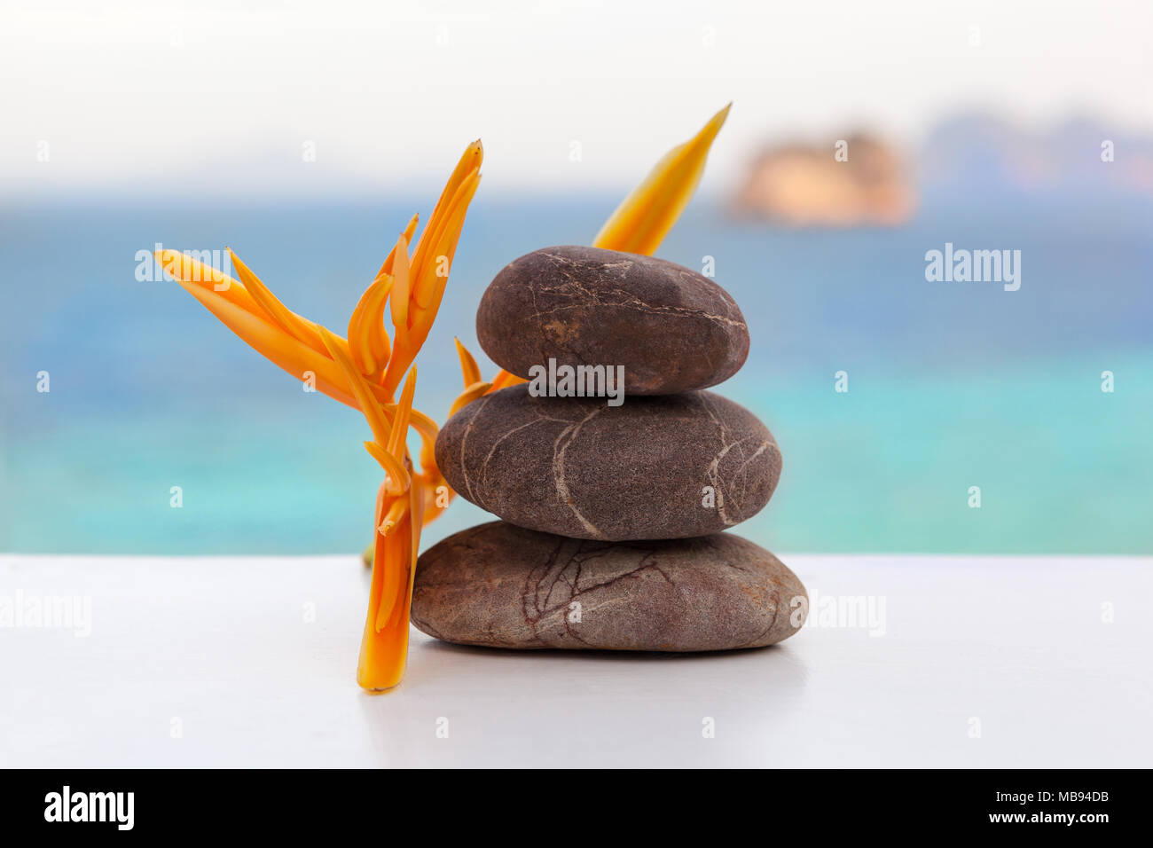 Rock cairn with tropical flour, turquise ocean in background. Zen ...