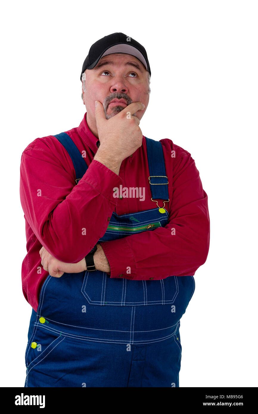 Overweight worker in overalls and peaked cap standing thinking with his ...
