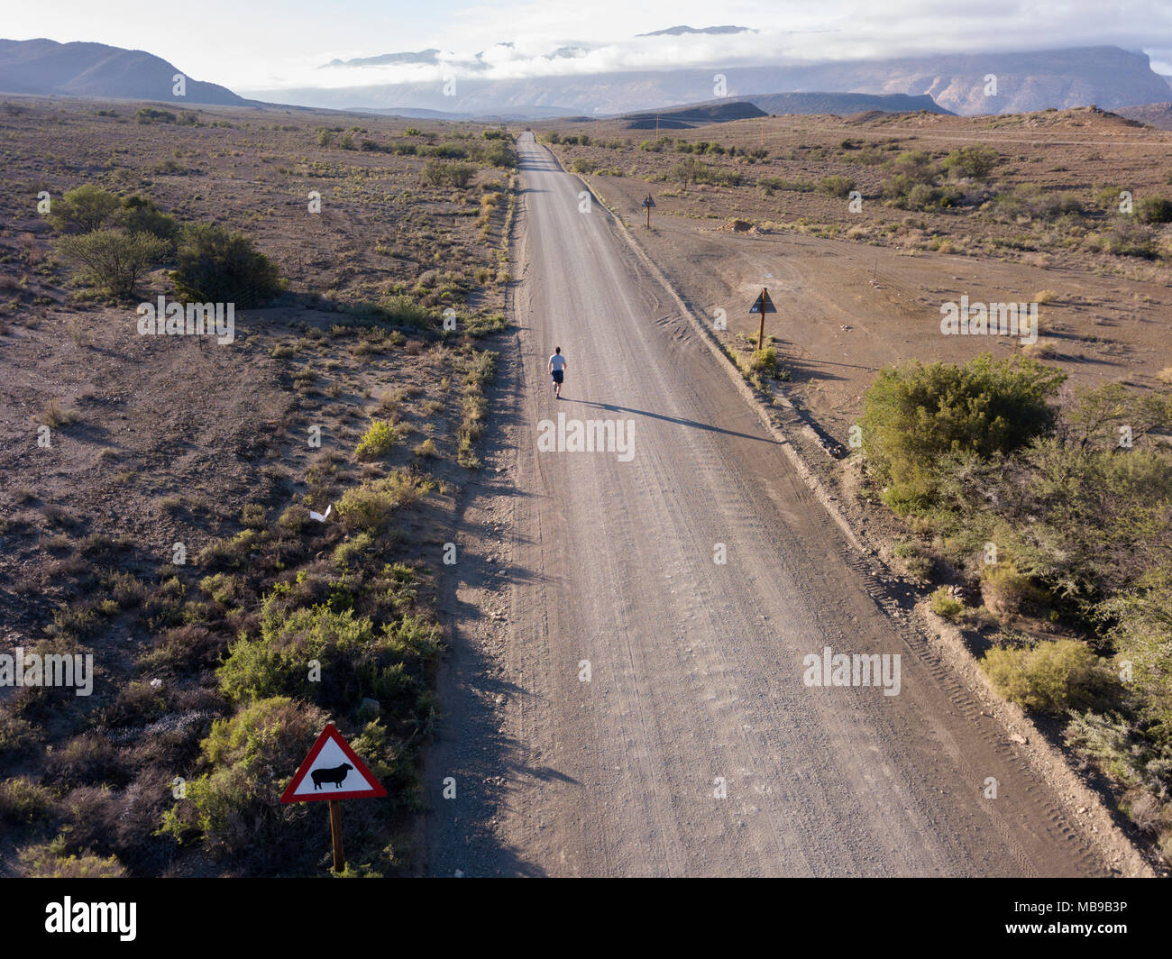 Man running on an open empty road in arid landscape Stock Photo - Alamy