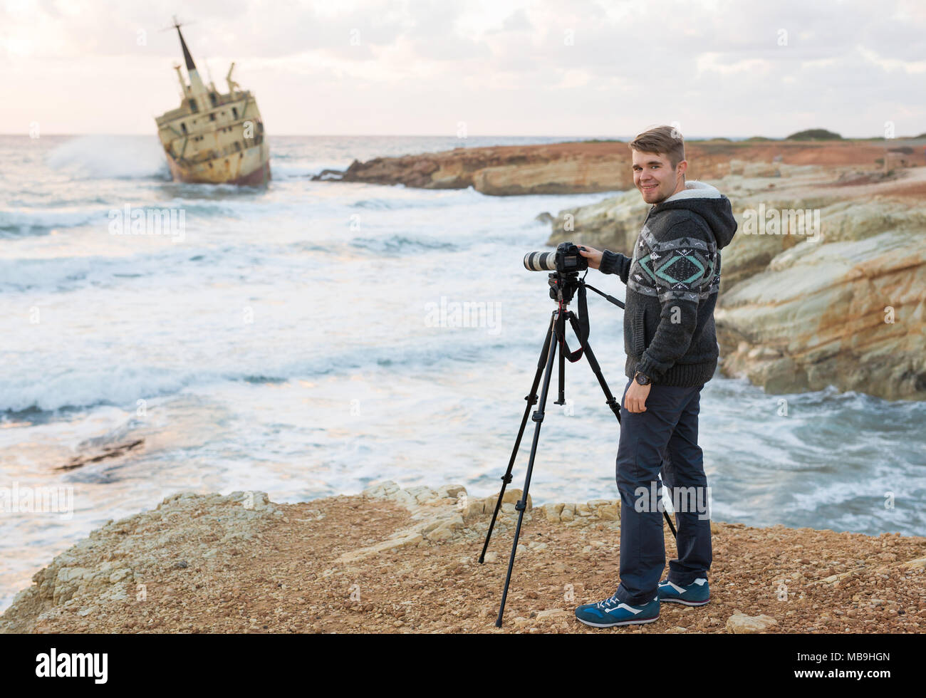 Young photographer with backpack making photos of sea and rocks with ...