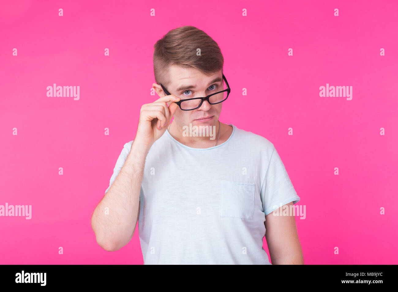 Curious handsome young man in blue shirt looking over lowered ...