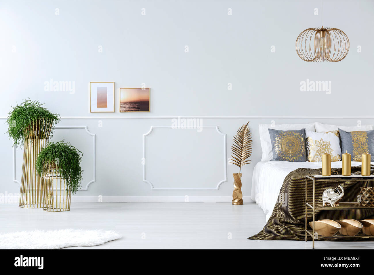 Plants in golden pots, photos and double bed in elegant bedroom ...
