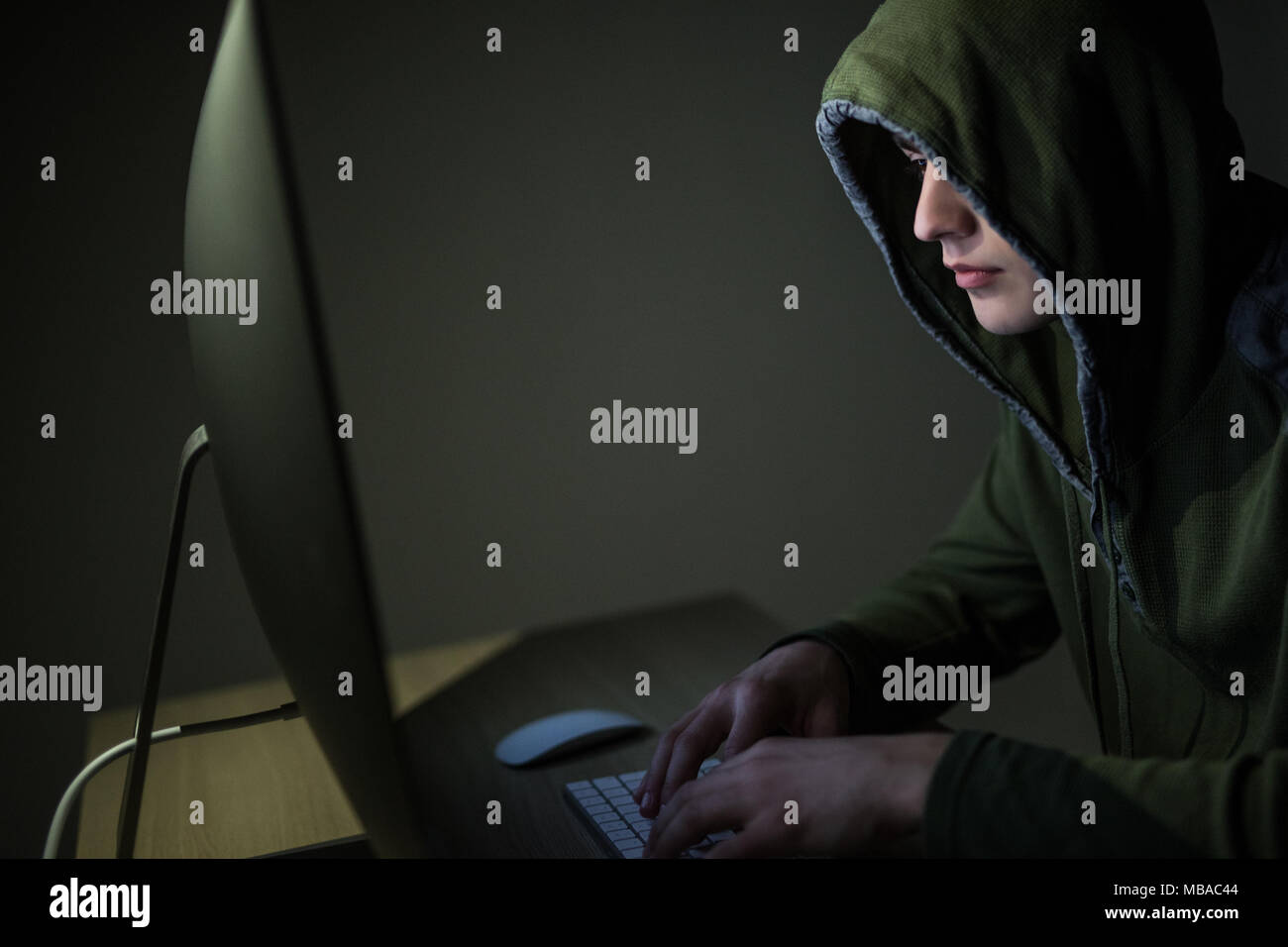 A hacker in a hood on a dark background hacking computer networks Stock ...