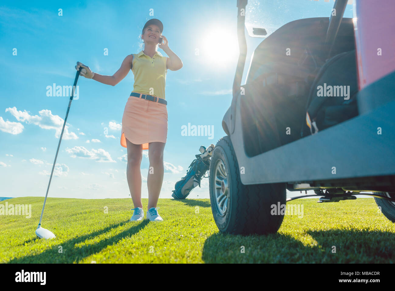 Full length of an active woman talking on mobile phone on the golf ...