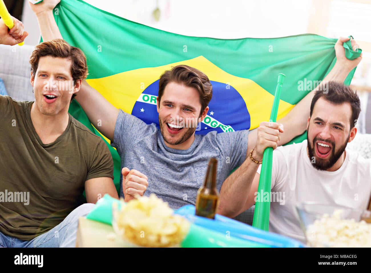 Happy male friends cheering and watching sports on tv Stock Photo - Alamy