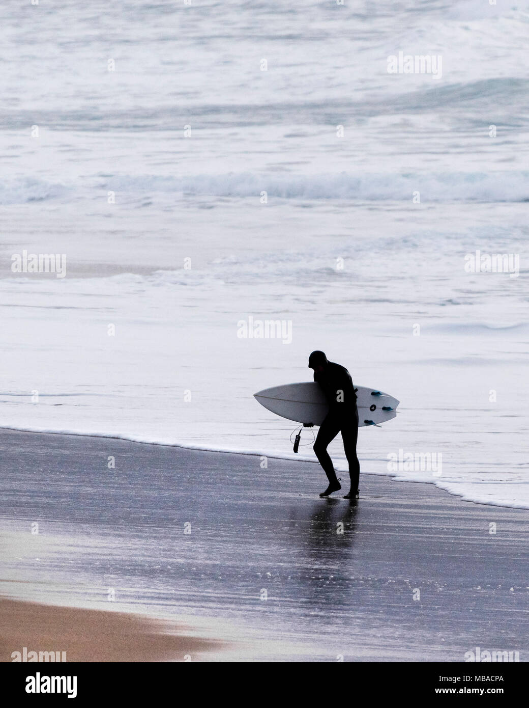The silhouette of an exhausted surfer carrying his surfboard as he ...