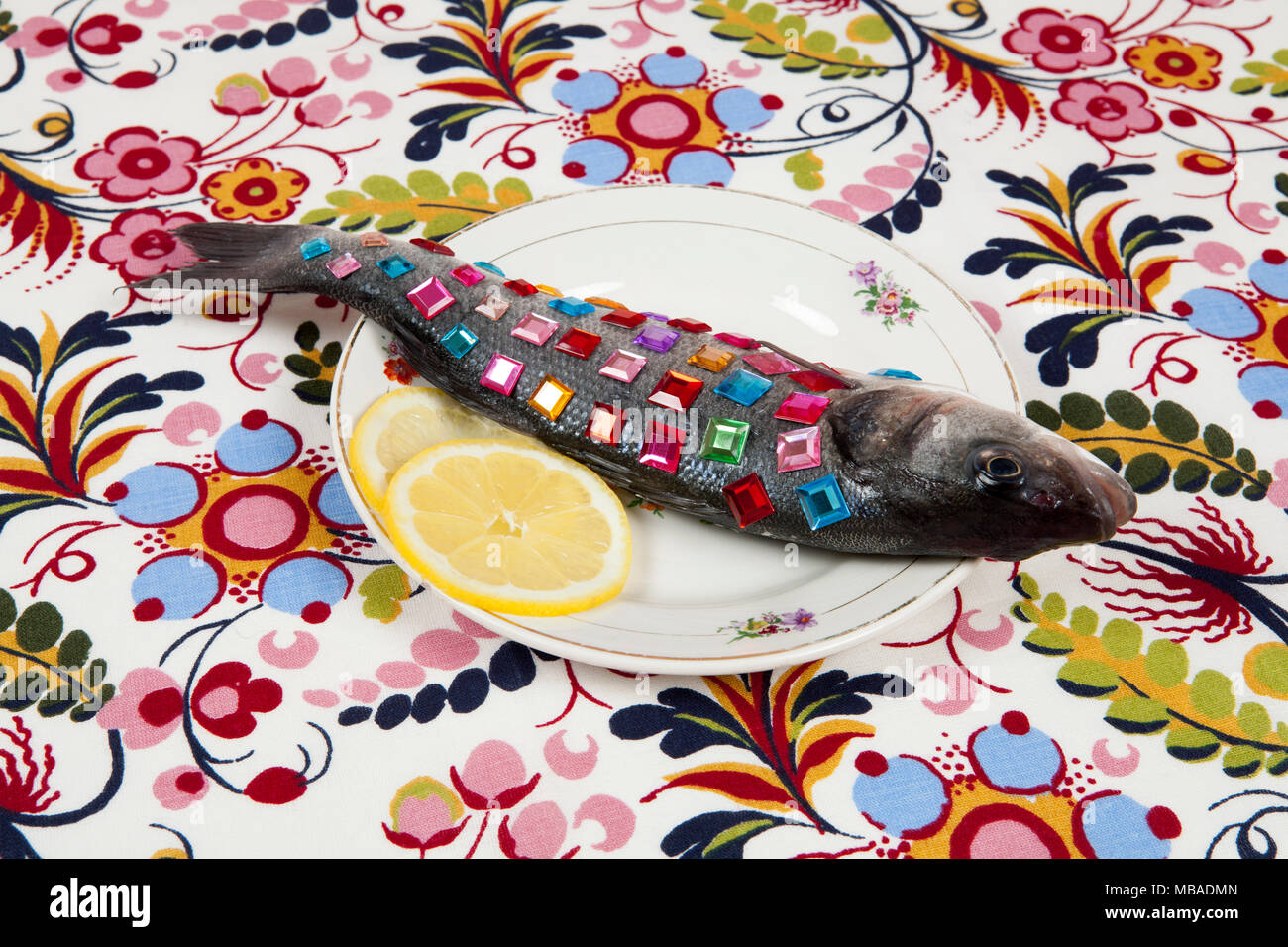 A bass fish covered with colorful precious stones inside a flower plate ...