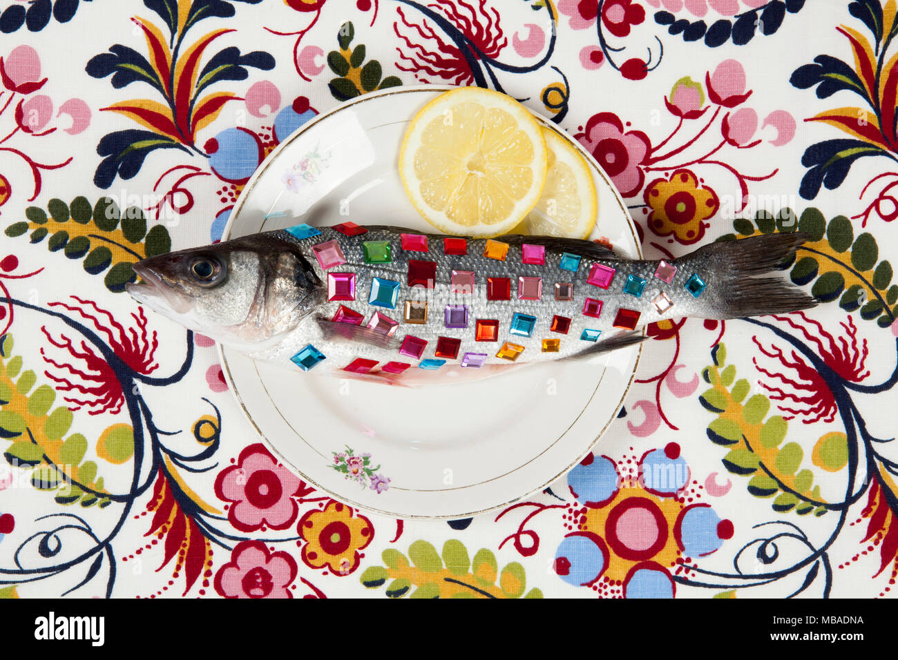 A bass fish covered with colorful precious stones inside a flower plate ...