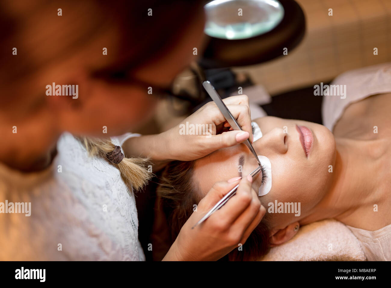 Beautician applying extended eyelashes to model. Top view Stock Photo ...