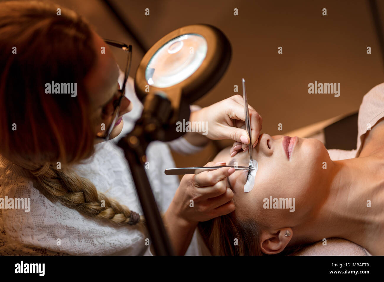 Beautician applying extended eyelashes to model at the beauty salon ...