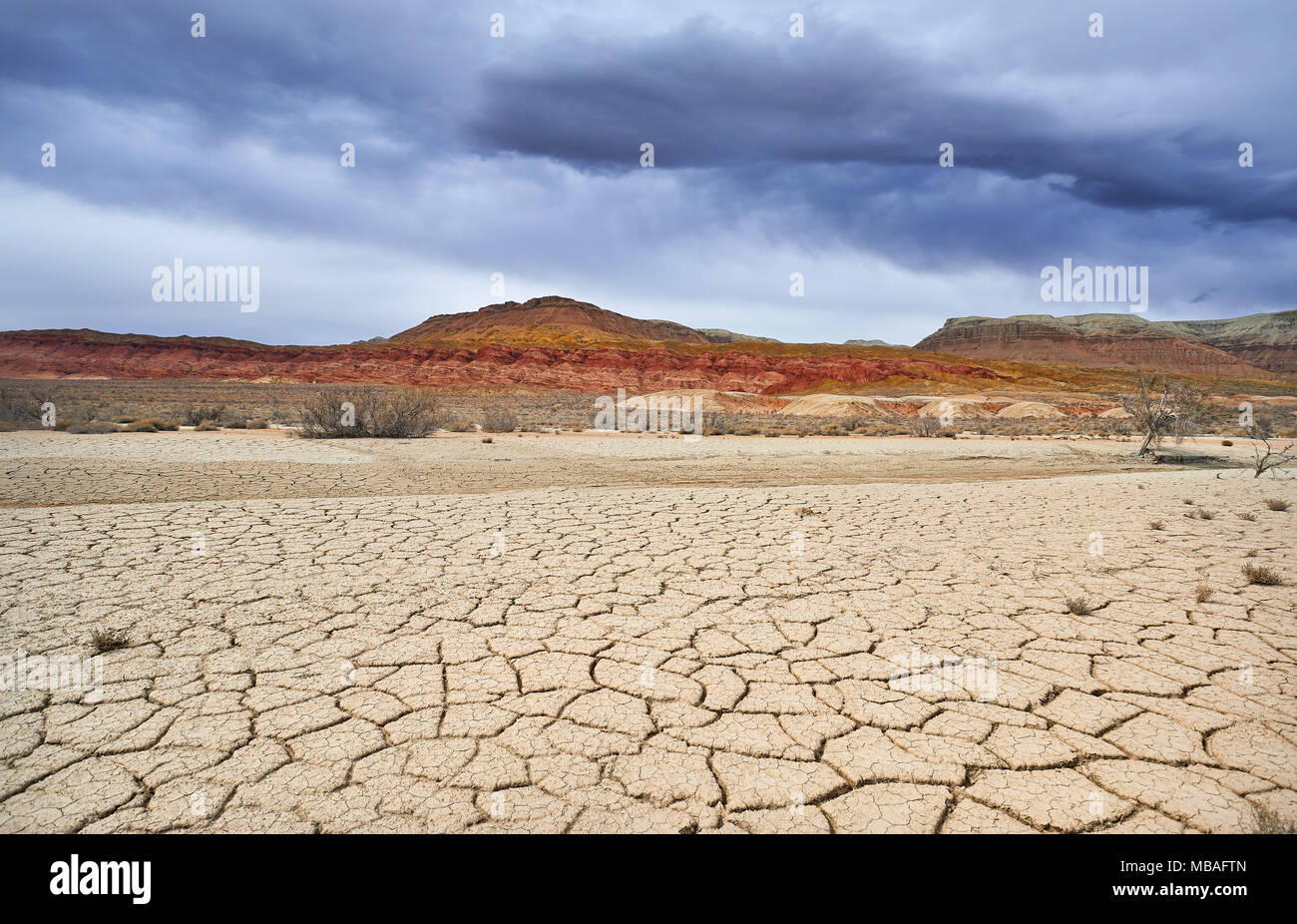 Dry cracked ground in Desert Park and rainy clouds above mountains ...