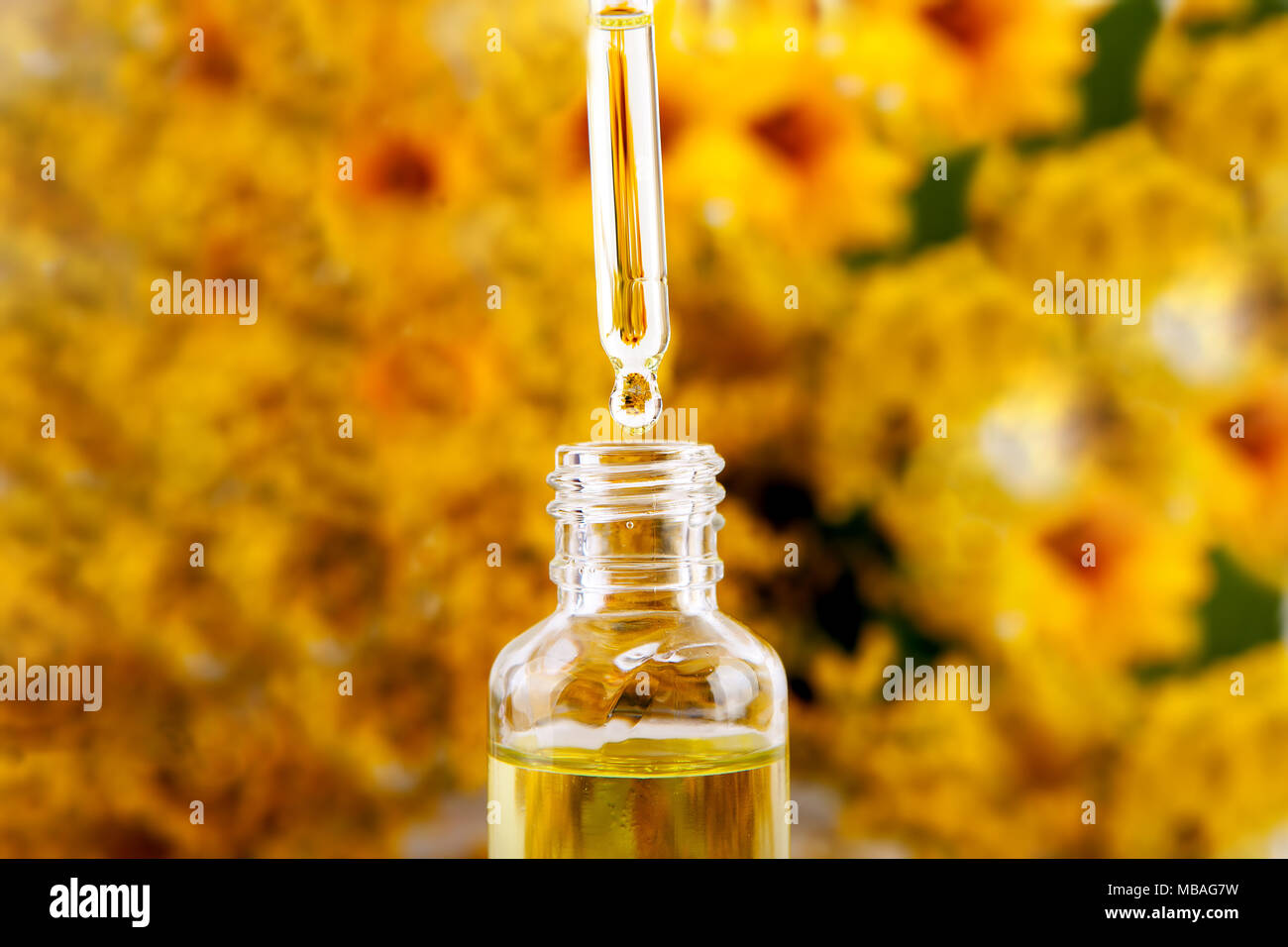 Drop falling from dropper of essential oil, aromatherapy essence, or ...