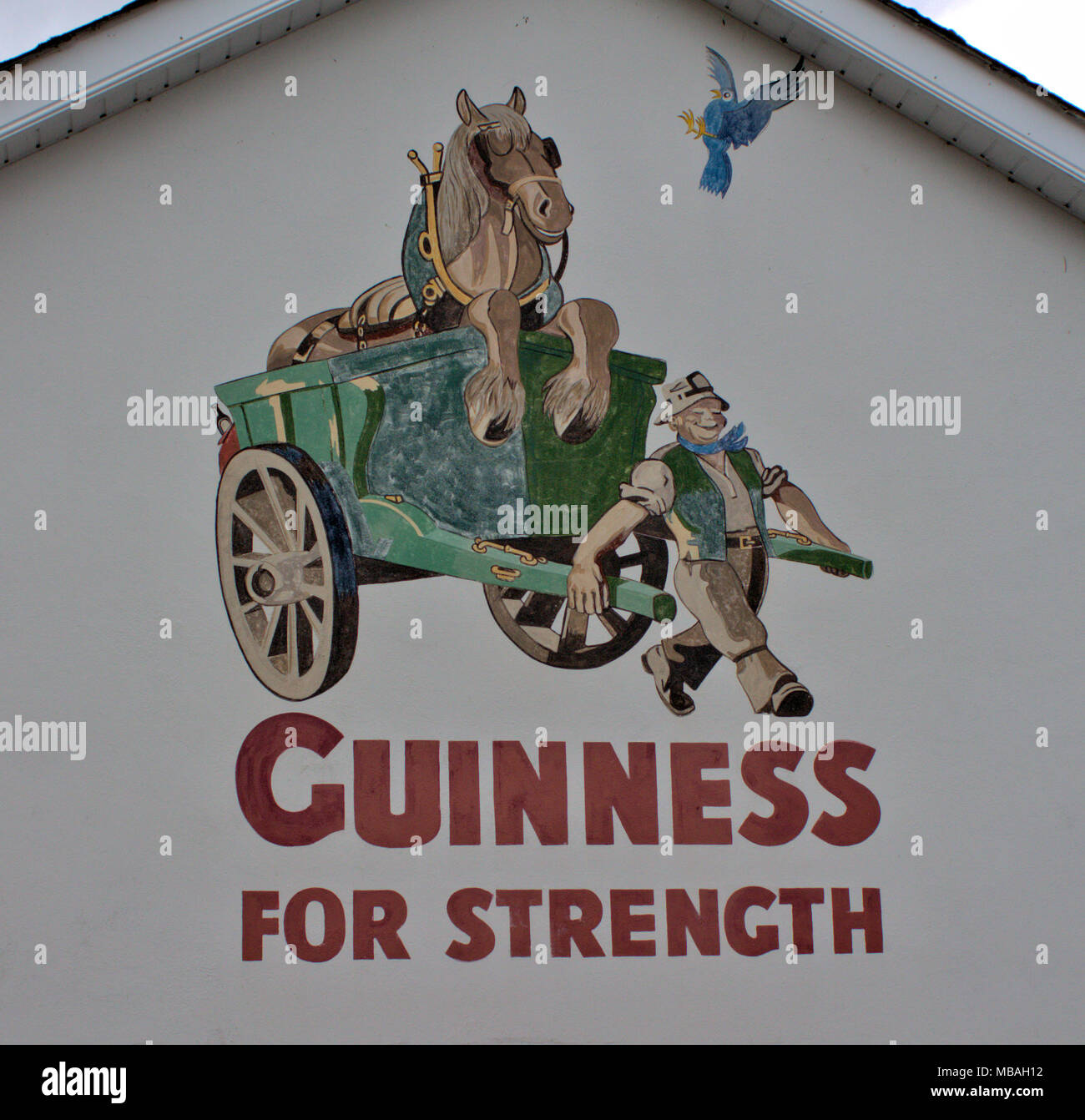 painting on a building wall of a farmer pulling a horse and cart for a ...