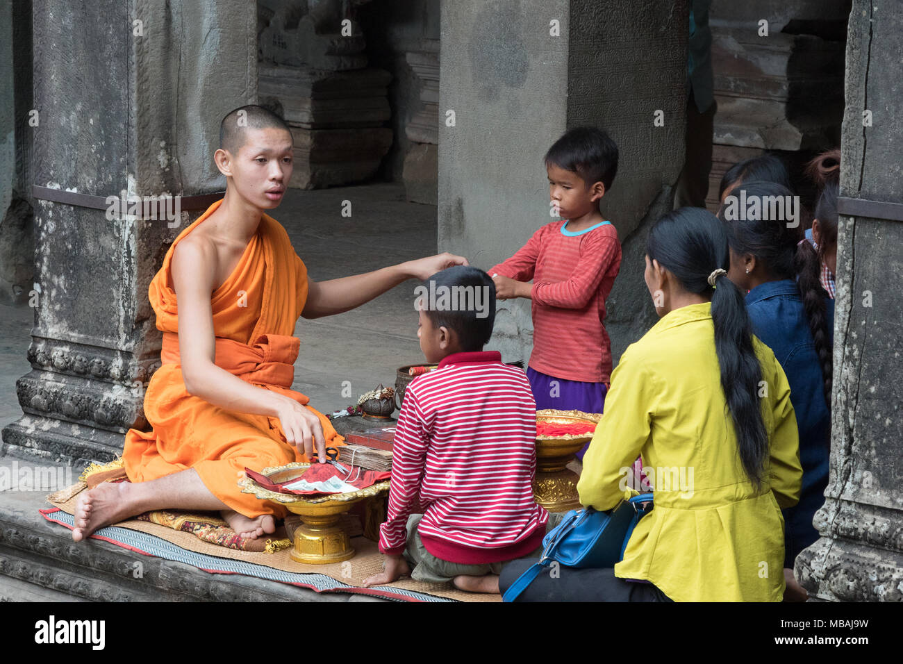 A Buddhist monk giving a blessing to a cambodian local family, Angkor ...