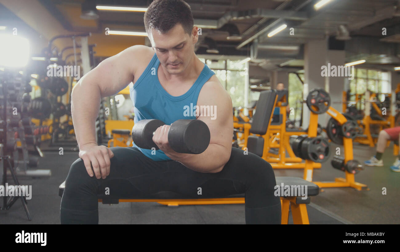 Young strong man exercising with dumbbells in the gym Stock Photo - Alamy