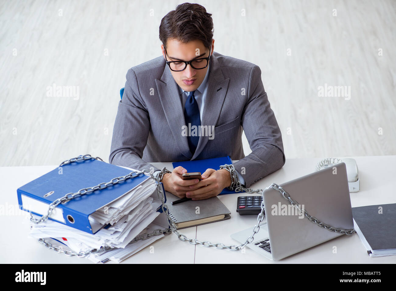 Busy employee chained to his office desk Stock Photo - Alamy