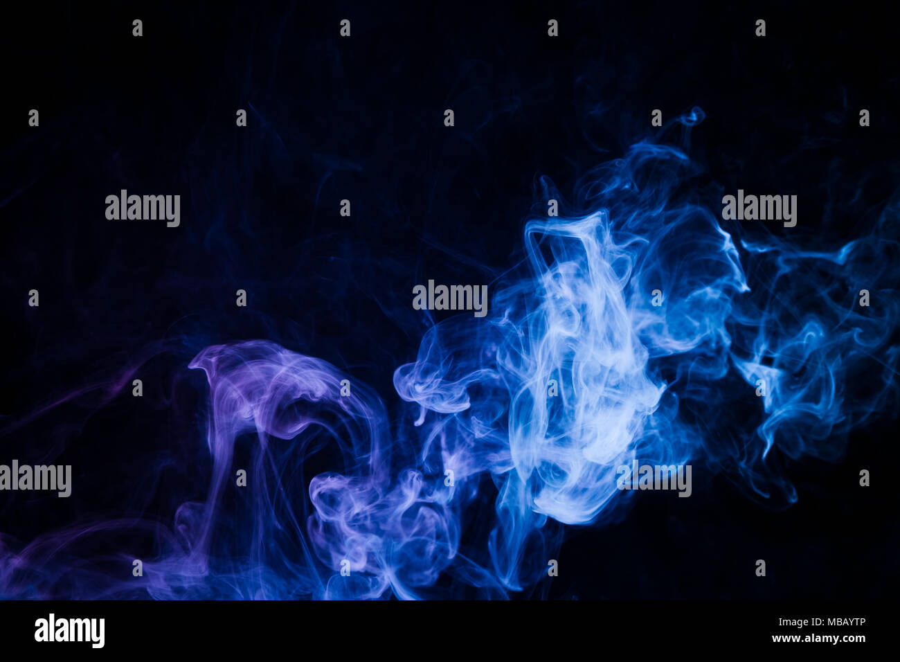 Dense multicolored smoke of blue colors on a black isolated background ...