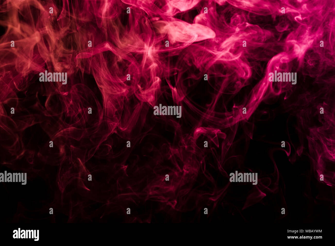 Thick pink and red colorful smoke on a black isolated background ...