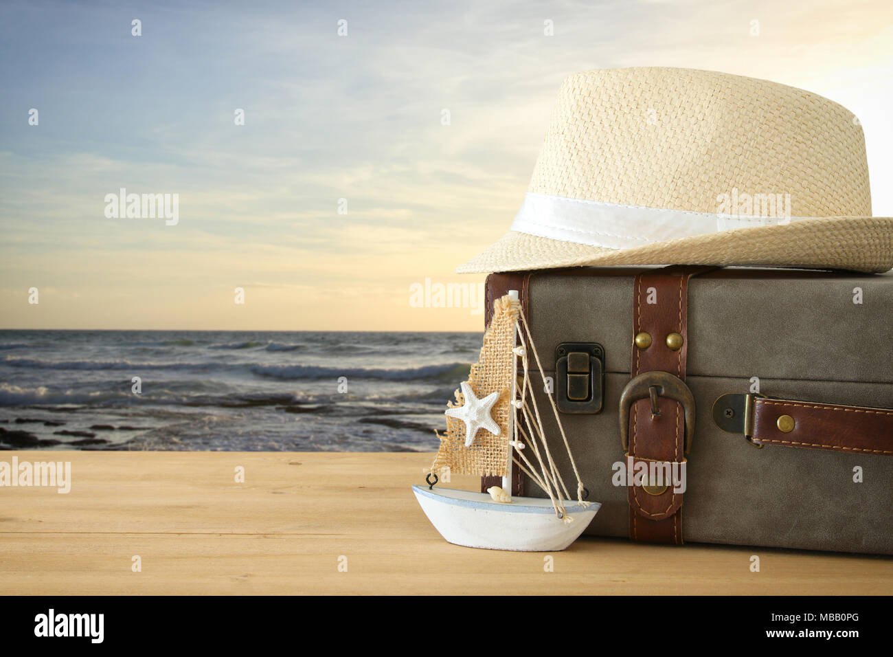 traveler vintage luggage, boat and fedora hat over wooden table infront ...