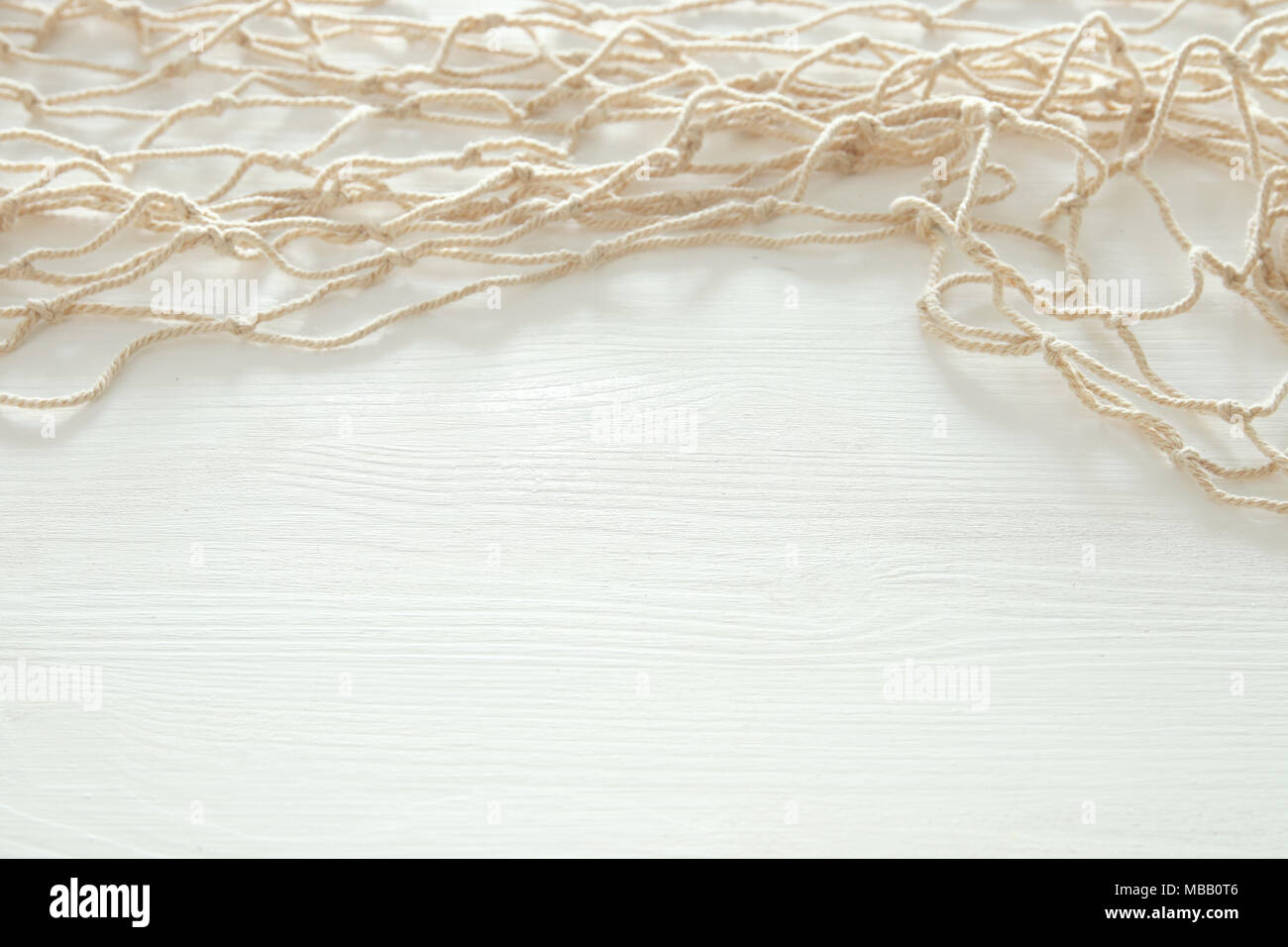Fishnet on white wooden background Stock Photo - Alamy