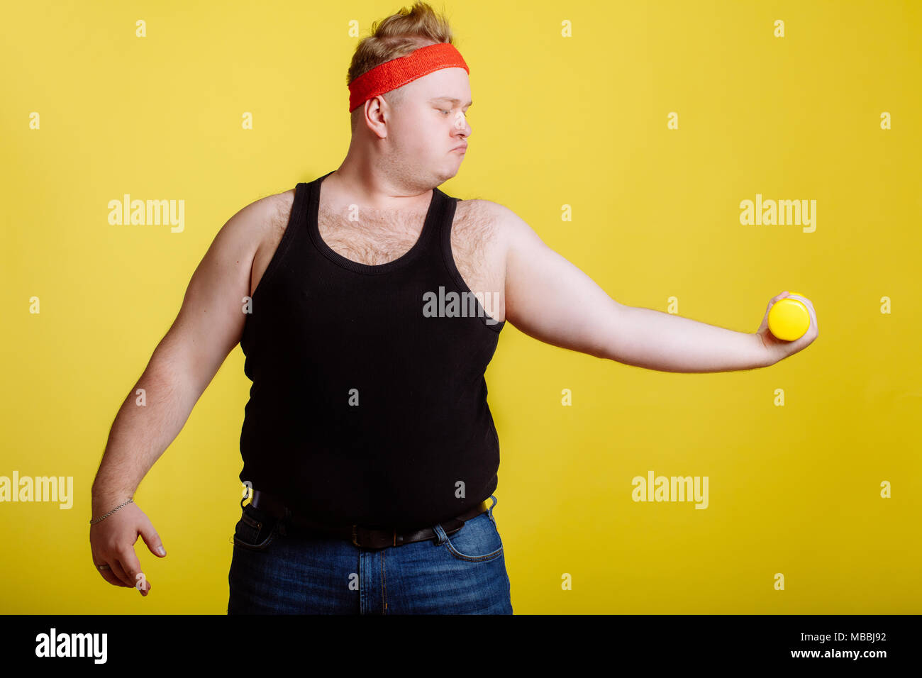 fat man with dumbbell on yellow background. Motivation for fat people ...