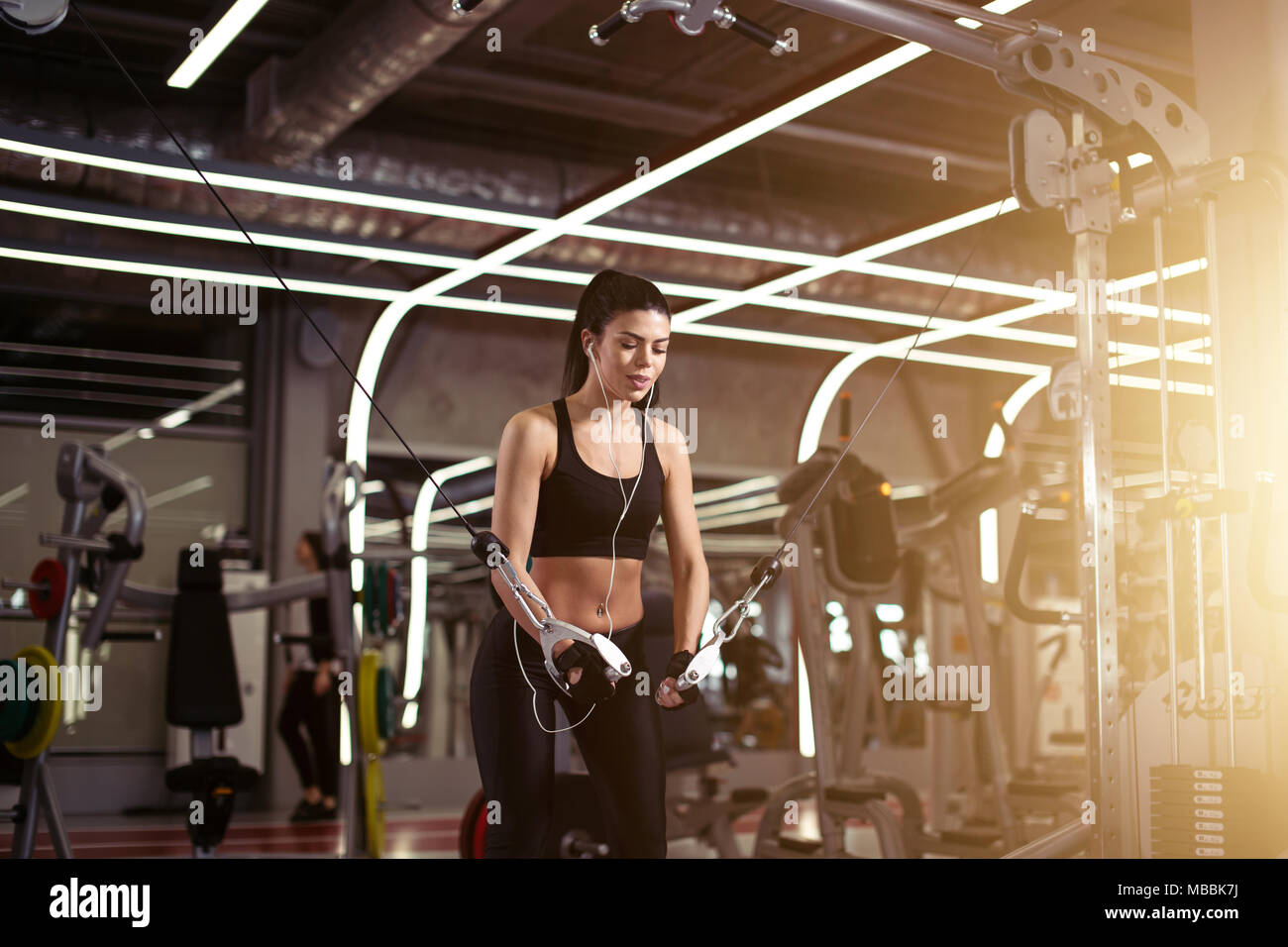 fit woman execute exercise with exercise-machine Cable Crossover in gym ...