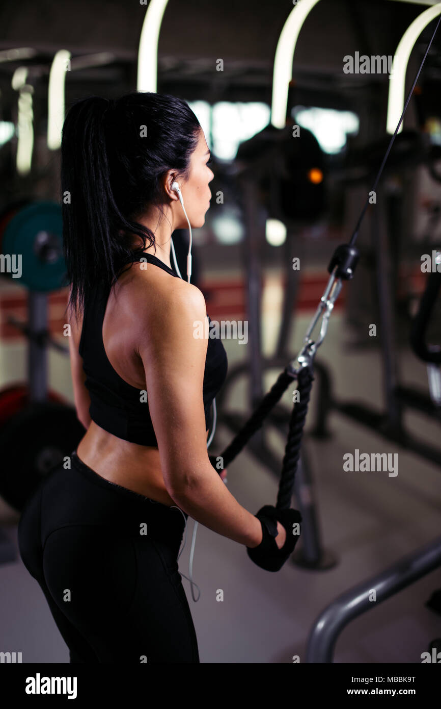 rear view fit woman execute exercise with exercise-machine Cable ...