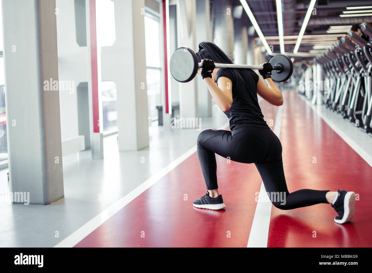 Fit girl doing lunges with barbell in modern gym Stock Photo - Alamy