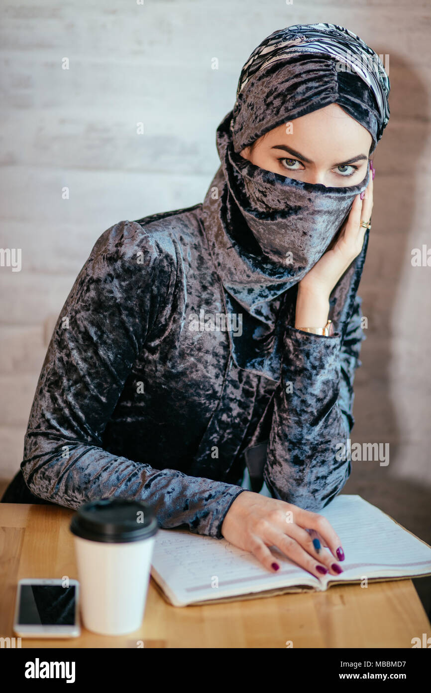 muslim Woman writing on her notebook in cafe Stock Photo - Alamy
